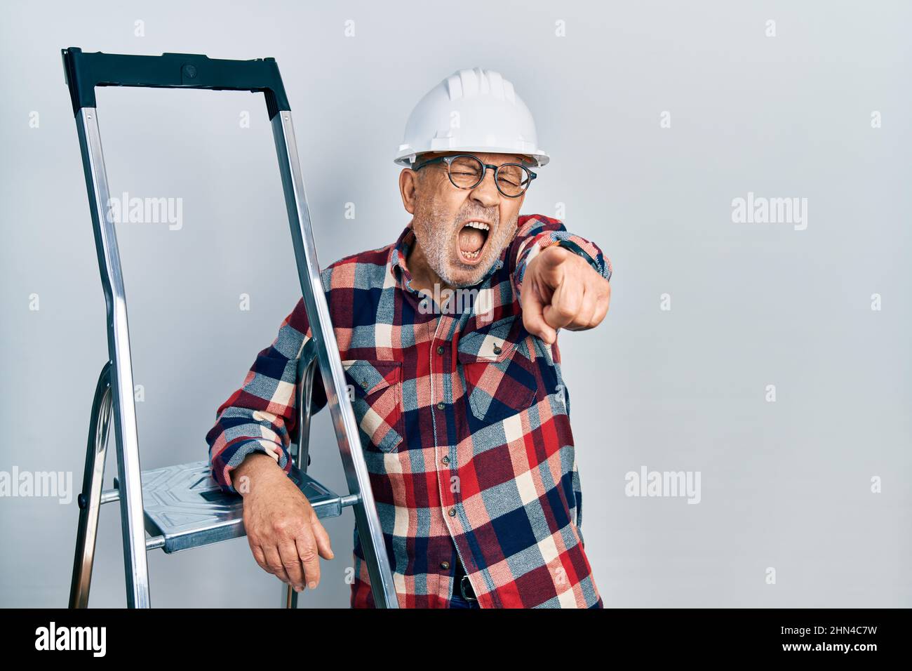 Handsome mature handyman close to construction stairs wearing hardhat ...