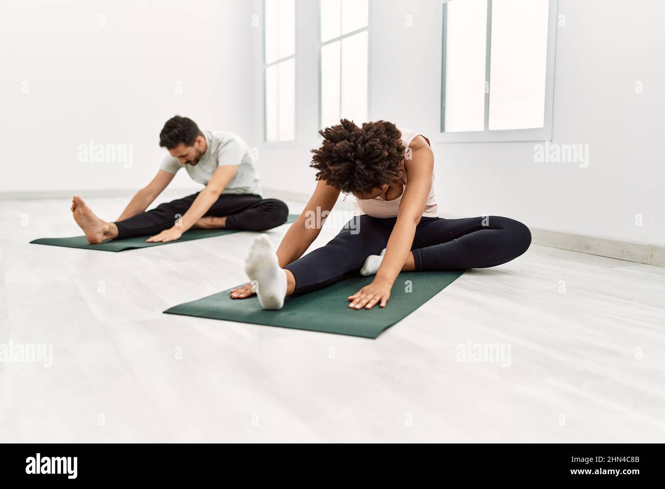 Young african american woman and hispanic man exercising at pilates ...