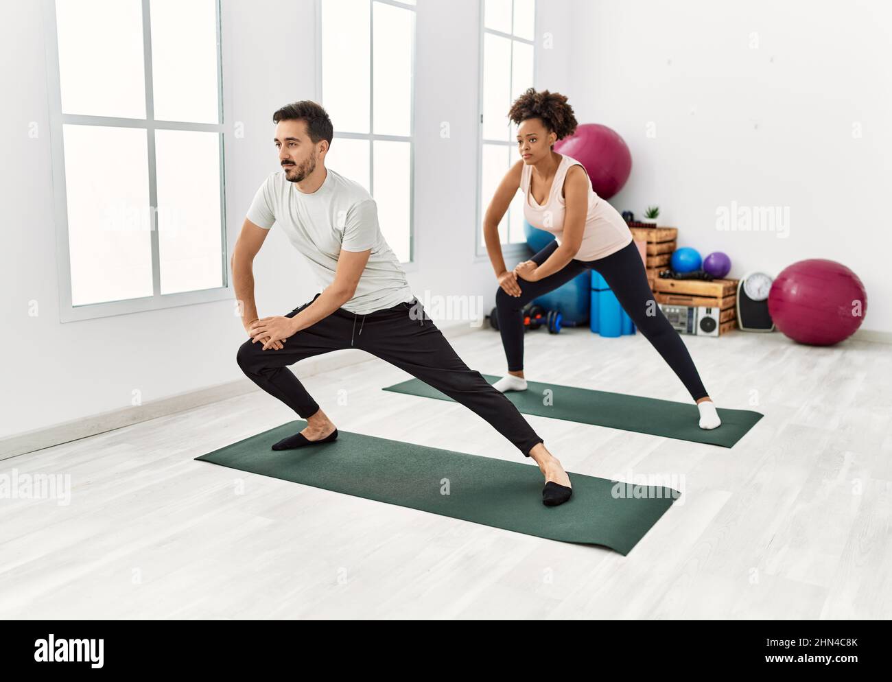 Young african american woman and hispanic man exercising at pilates ...