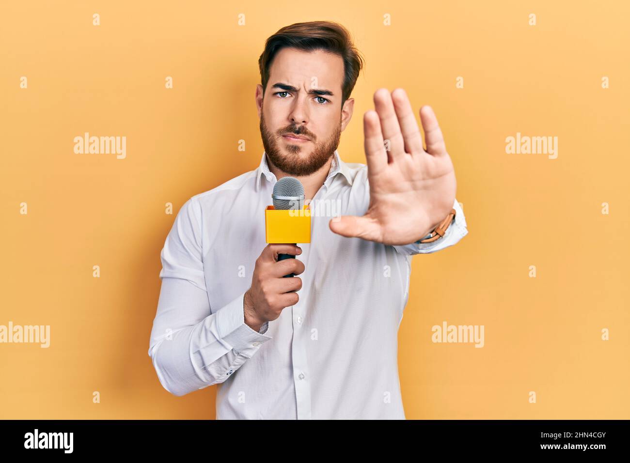 Handsome caucasian man with beard holding reporter microphone with open ...