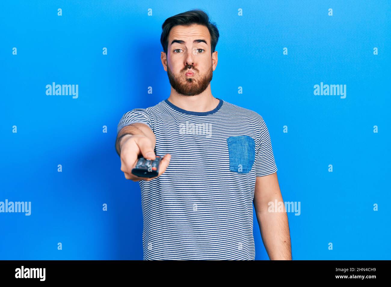 Handsome caucasian man with beard holding television remote control ...