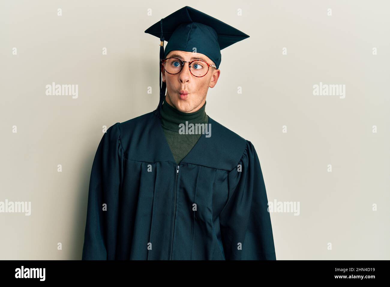Young caucasian man wearing graduation cap and ceremony robe making ...