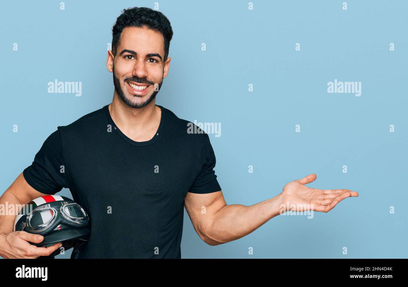 Hispanic man with beard holding motorcycle helmet celebrating victory ...