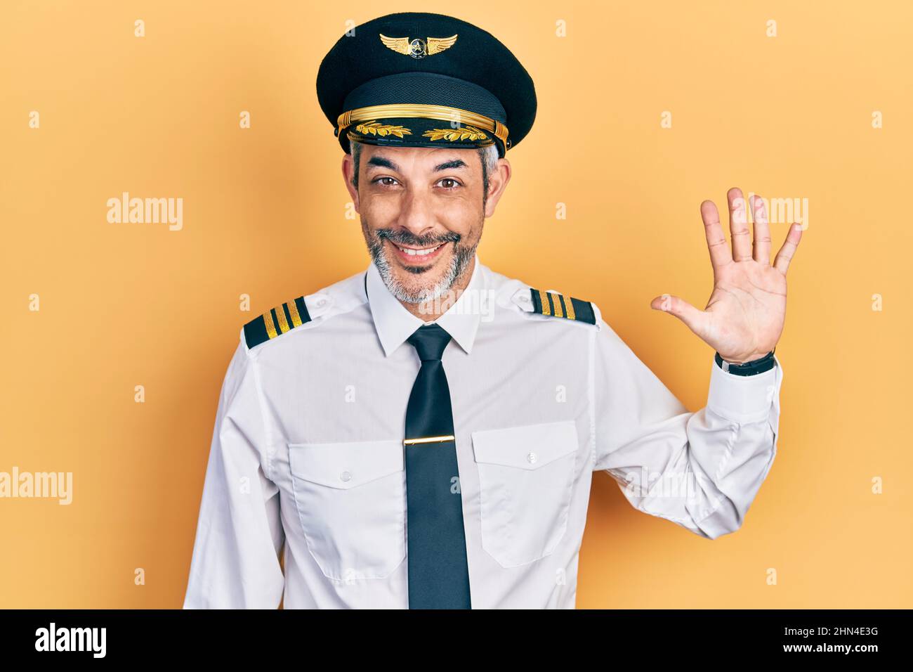 Handsome middle age man with grey hair wearing airplane pilot uniform ...