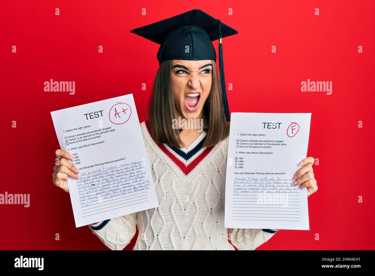 Young brunette girl wearing graduation cap showing exams angry and mad ...