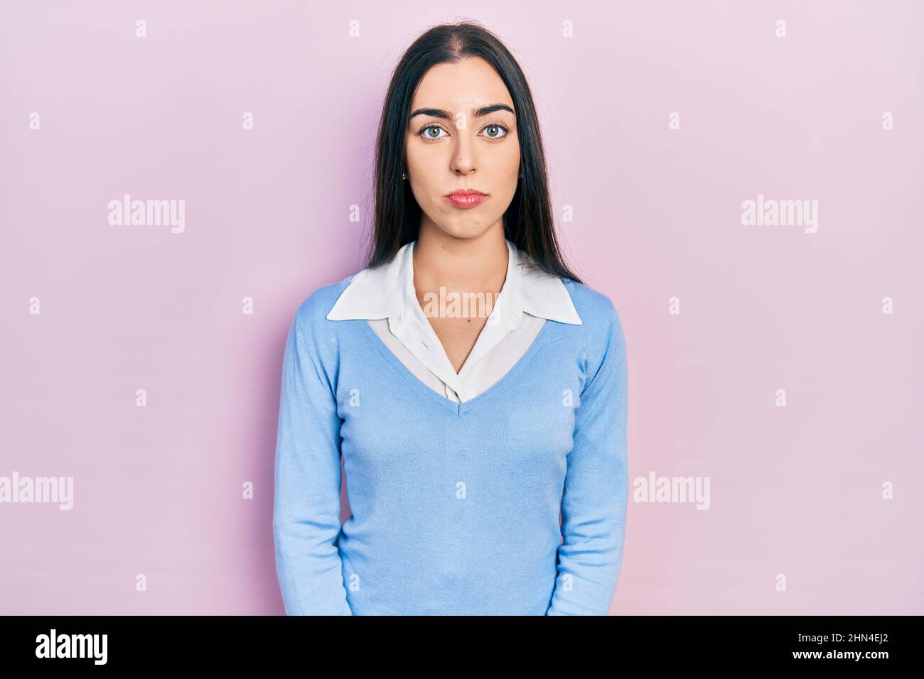 Beautiful woman with blue eyes standing over pink background depressed ...