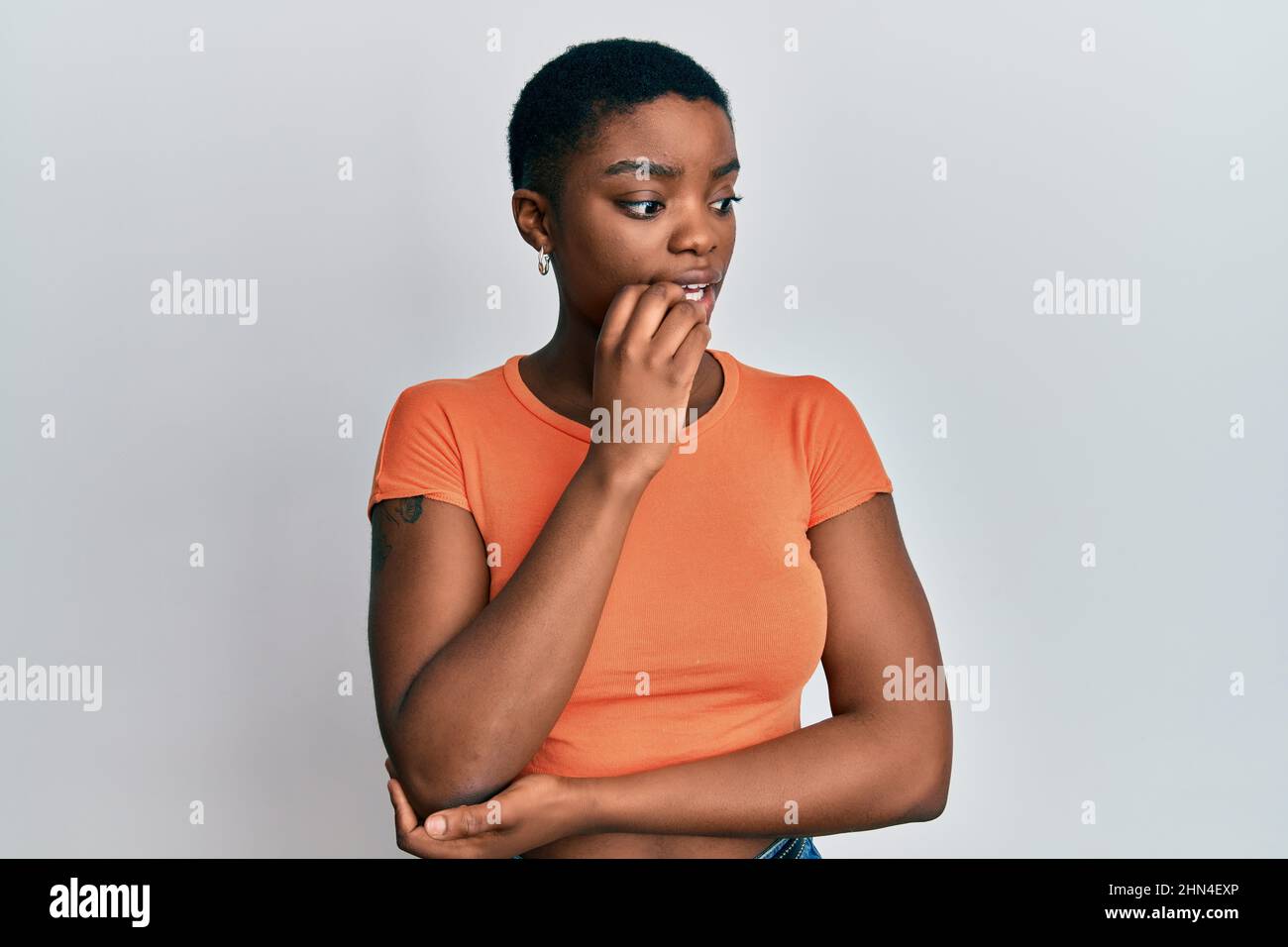 Young african american woman wearing casual orange t shirt looking ...