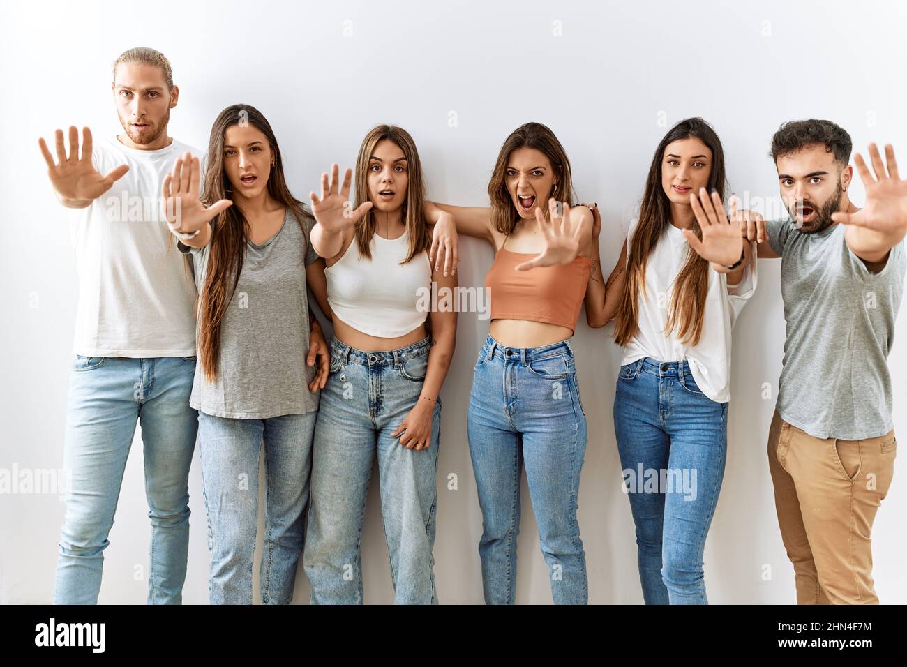 Group of young friends standing together over isolated background doing ...