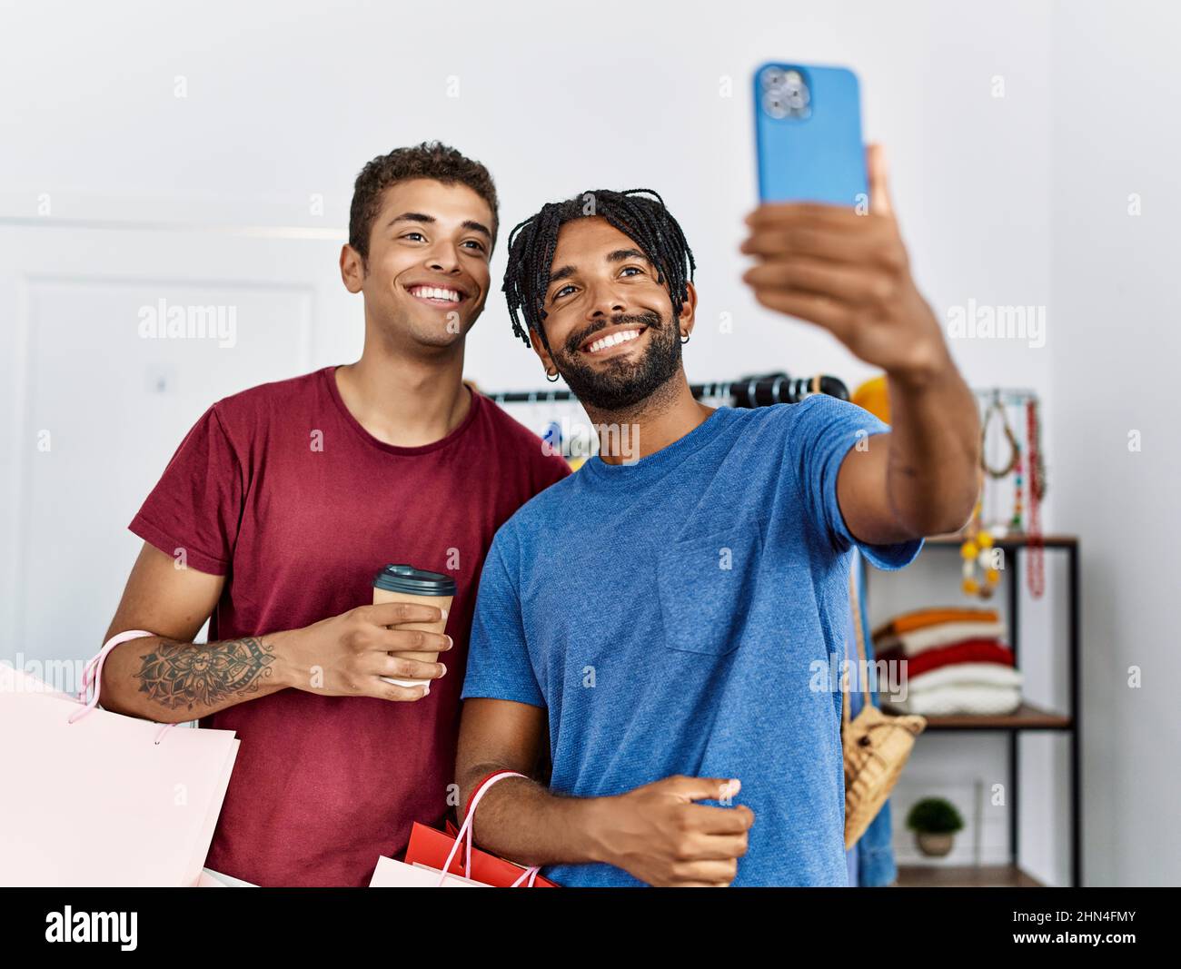 Two men friends holding shopping bags make selfie by the smartphone at ...
