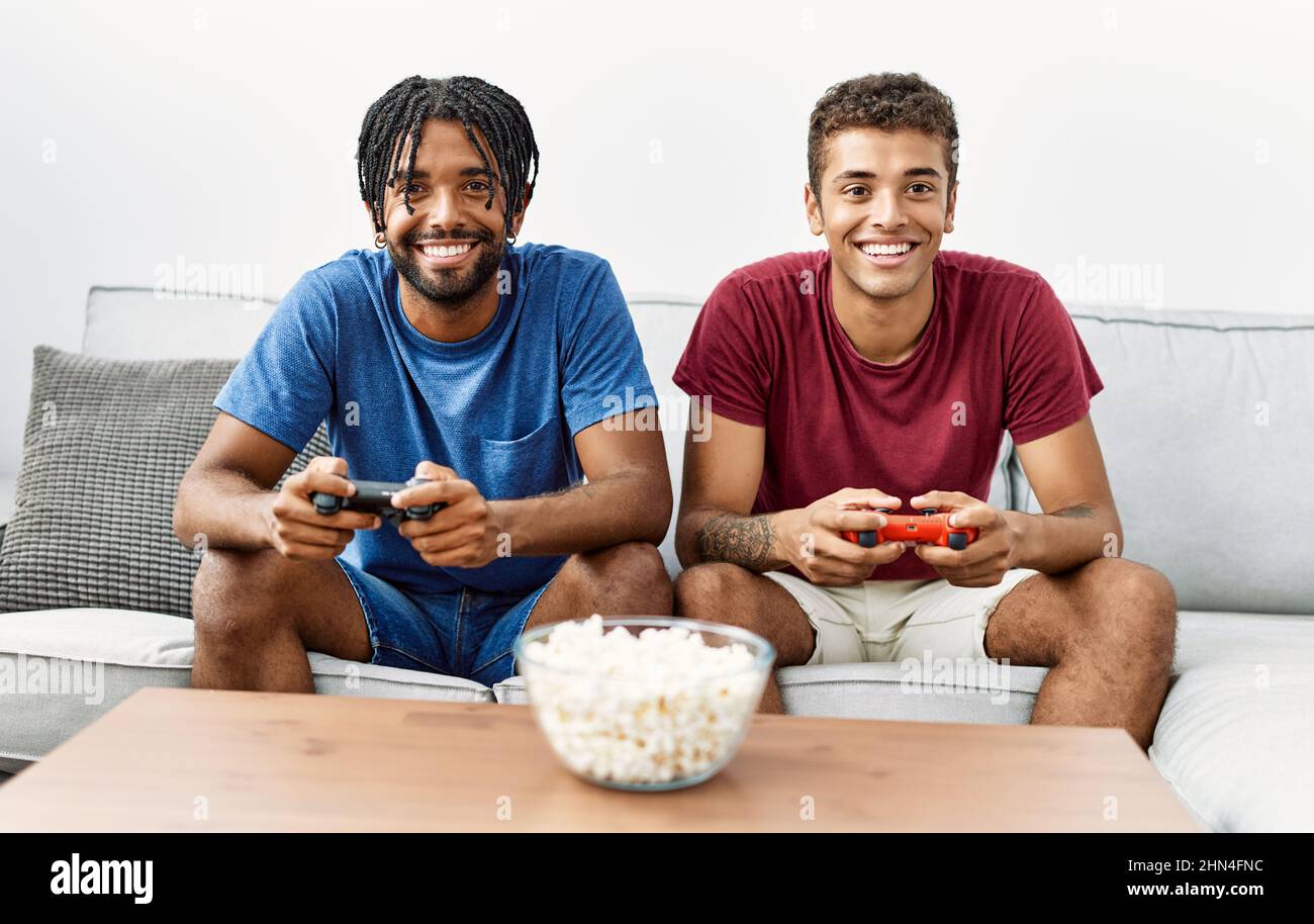 Two men friends playing video game sitting on sofa at home Stock Photo ...