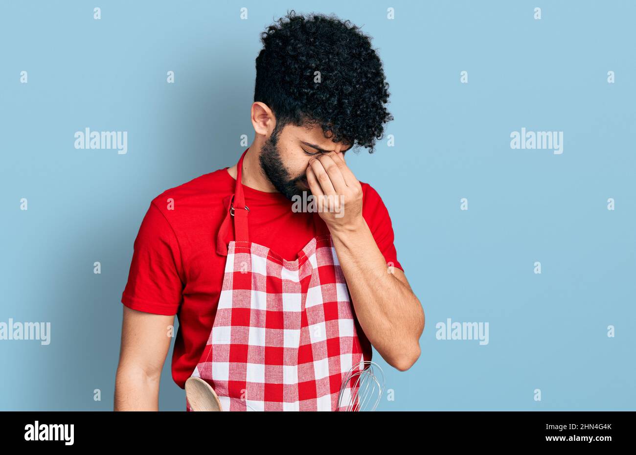 Young arab man with beard wearing cook apron tired rubbing nose and ...