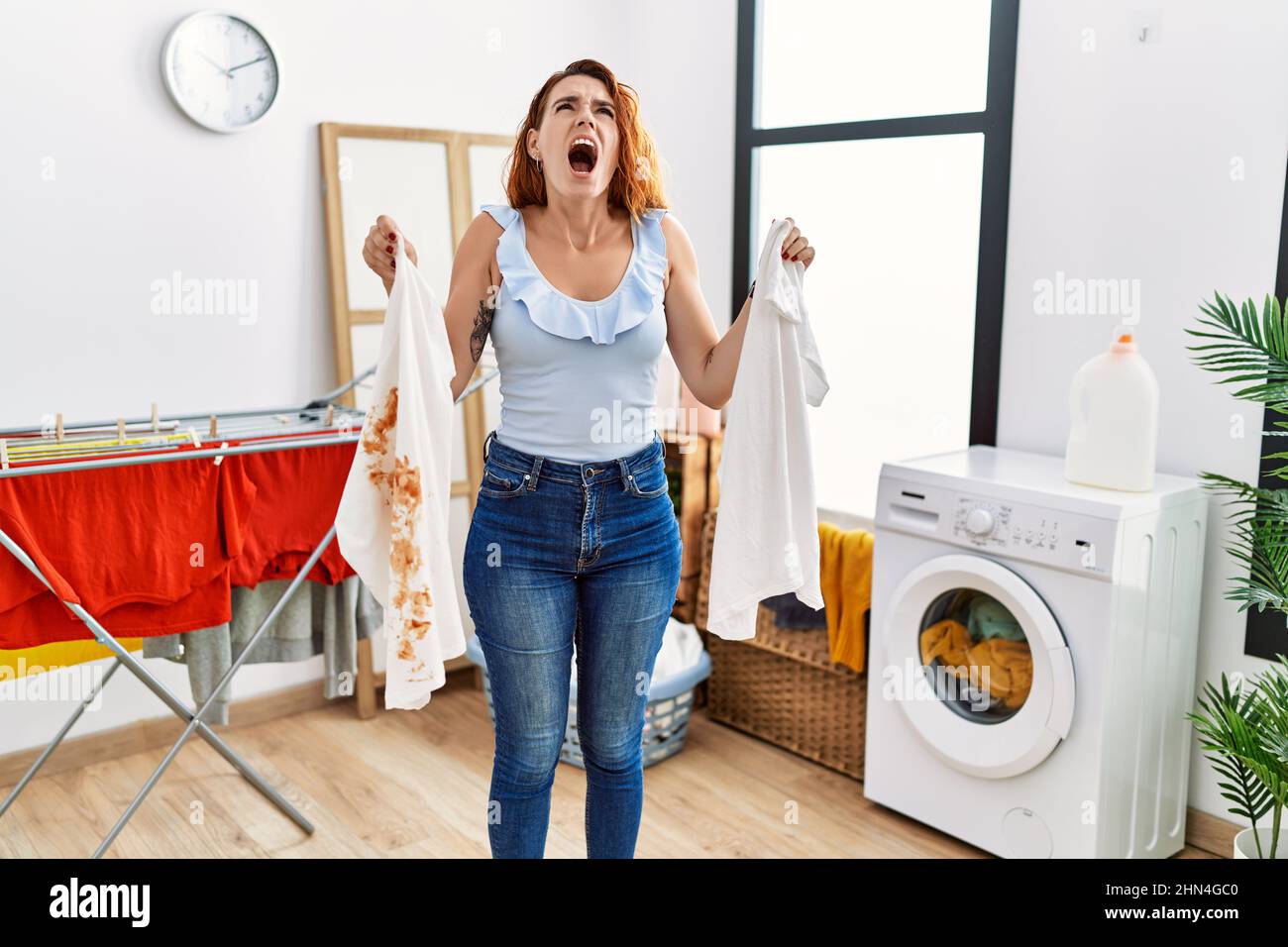 Young redhead woman holding clean white t shirt and t shirt with dirty ...