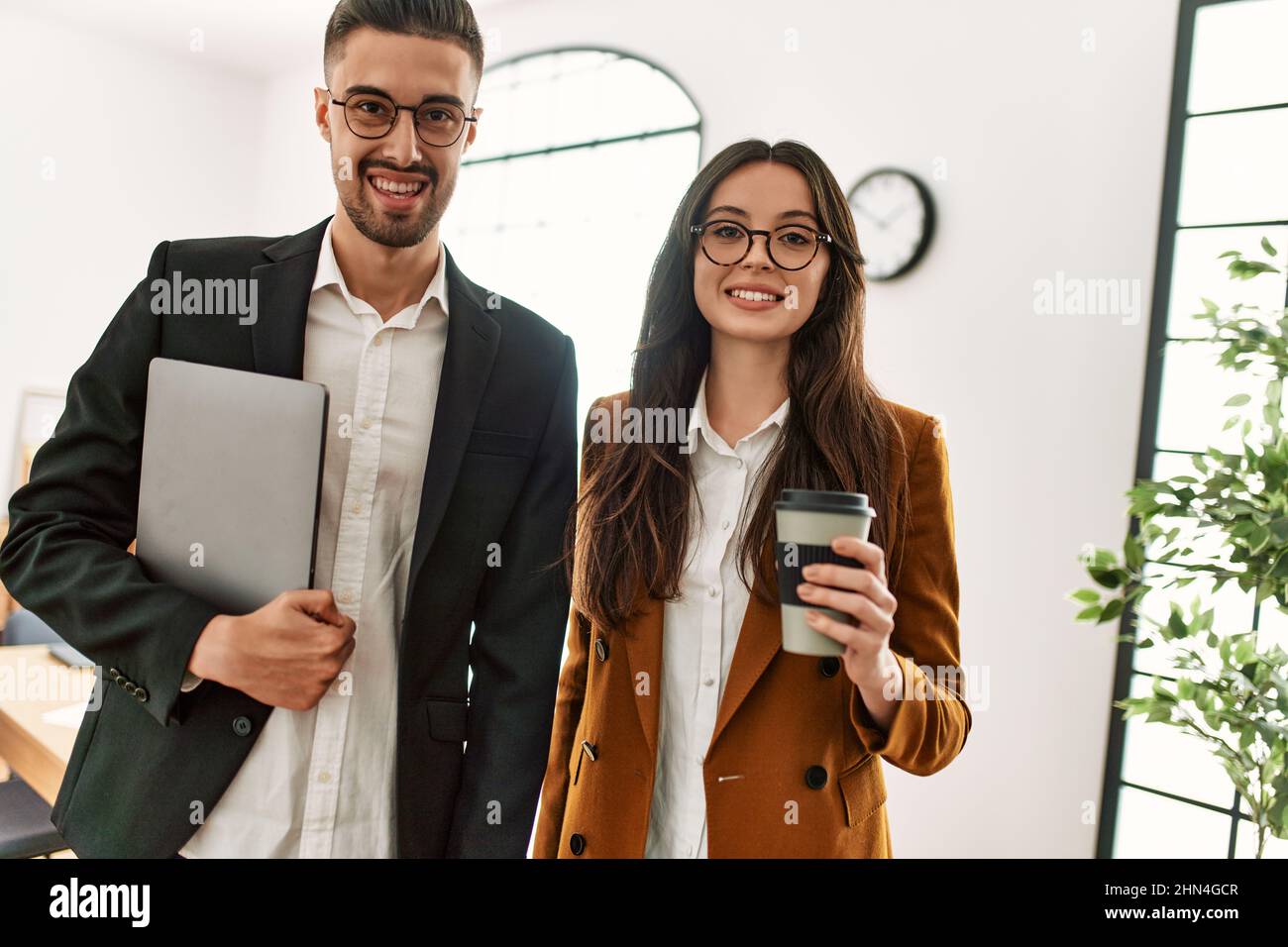 Two hispanic business workers smiling happy drinking coffee at the ...