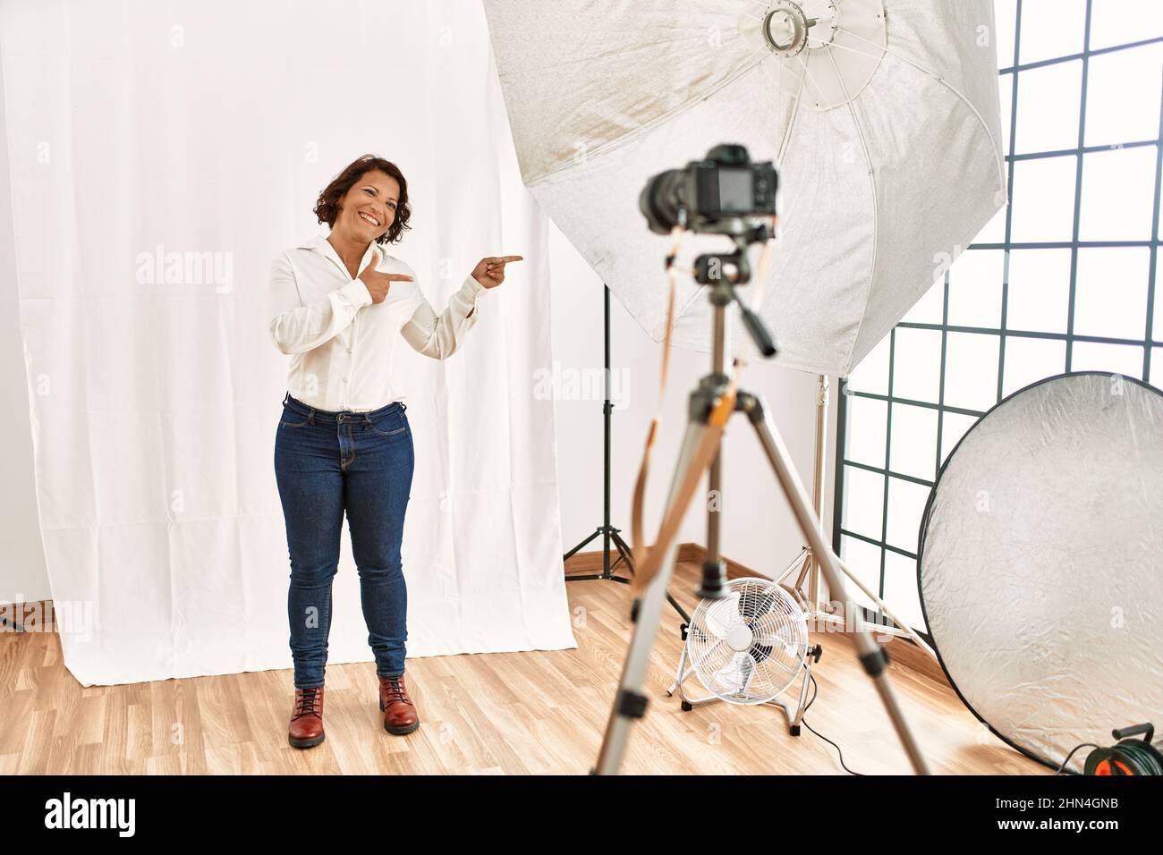 Middle age hispanic woman posing as model at photography studio smiling ...