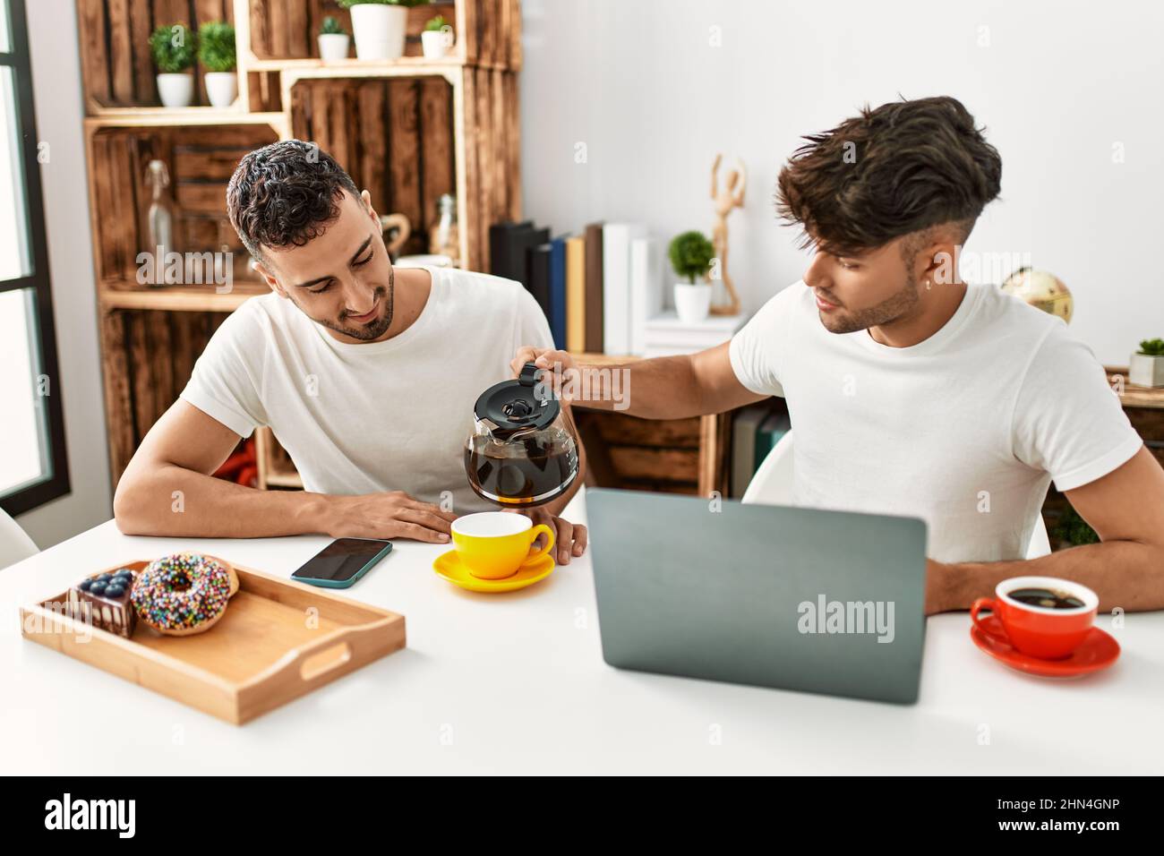 Two hispanic men couple pouring coffee having breakfast at home Stock ...