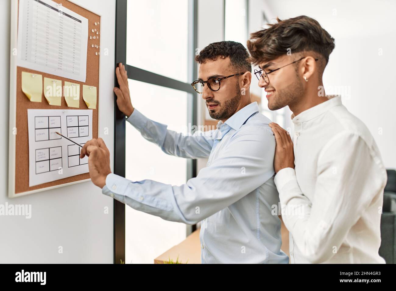 Two hispanic men couple writing on corkboard working at office Stock ...