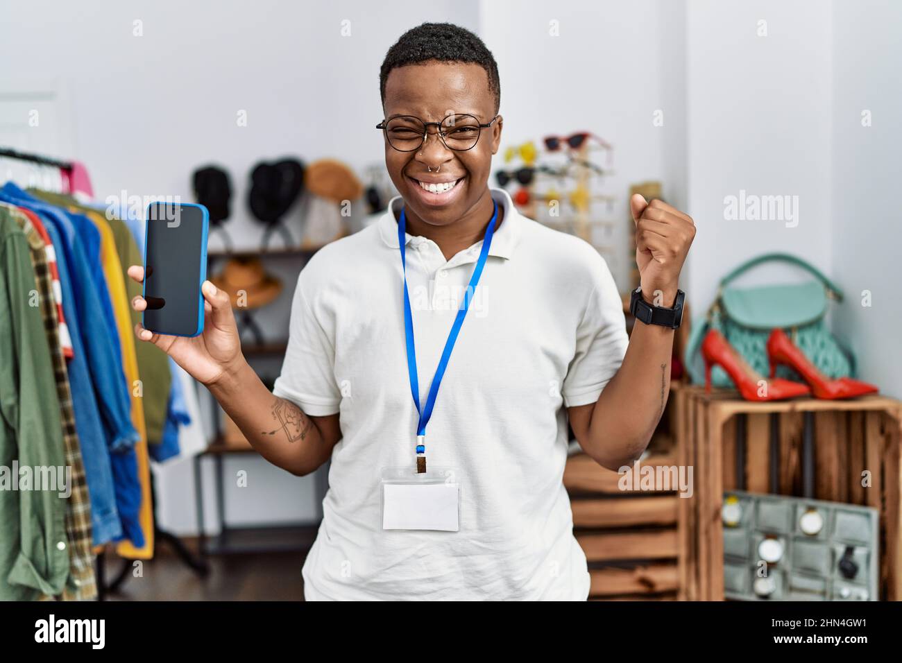 Young african man working at retail shop showing smartphone screen ...