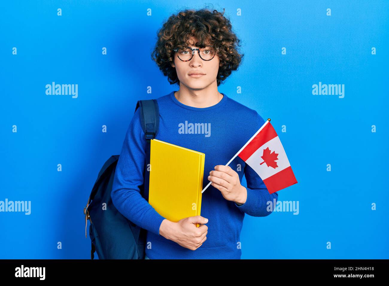 Handsome young man exchange student holding canada flag skeptic and ...