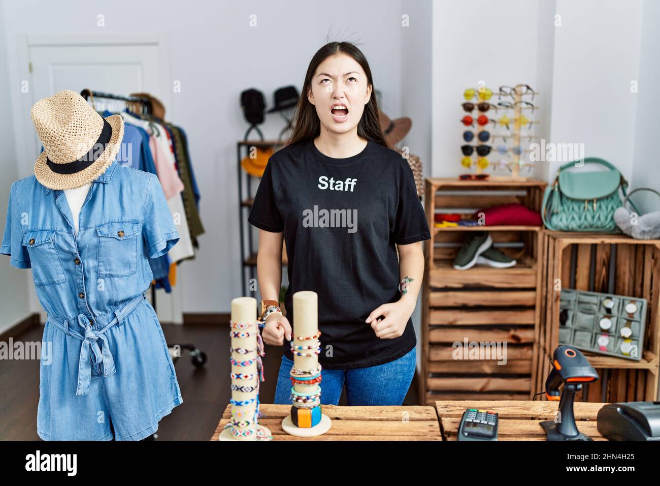 Young asian woman working as manager at retail boutique angry and mad ...