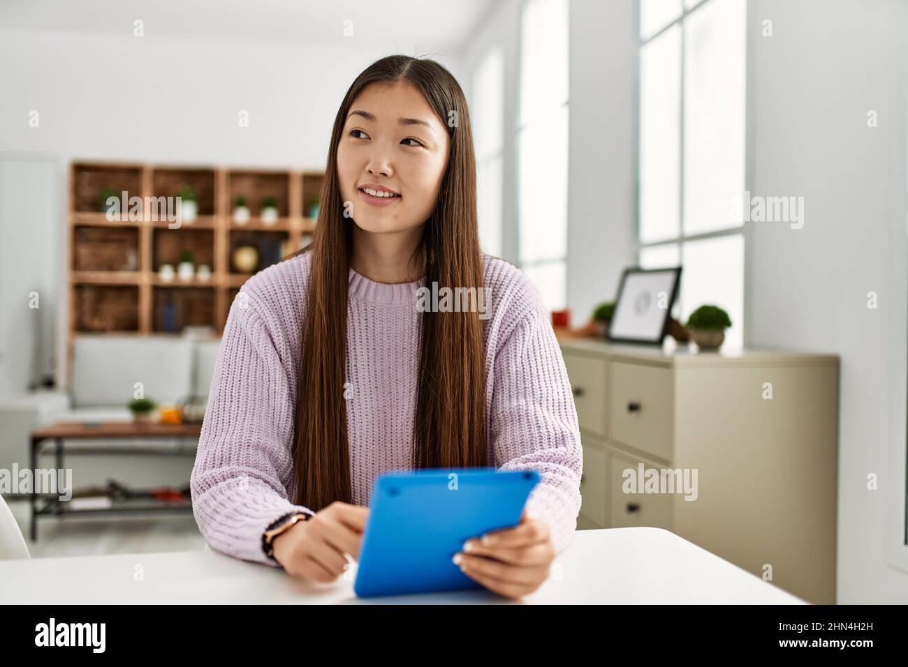 Young chinese girl using touchpad sitting on the table at home Stock ...