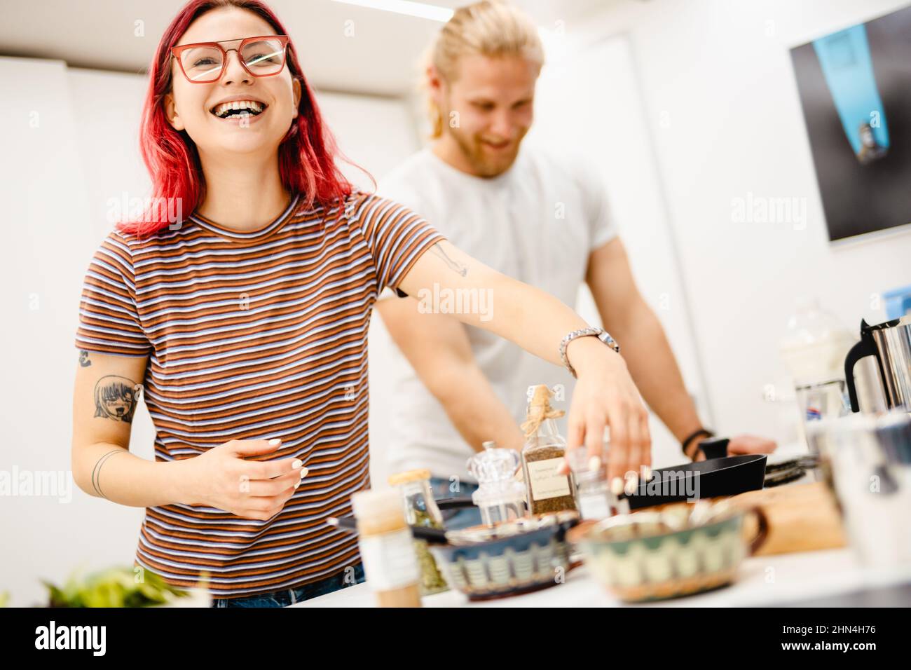 Young white couple laughing while cooking together in kitchen at home ...