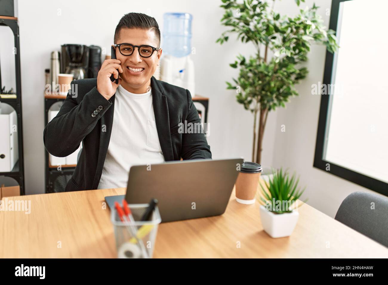 Young latin businessman smiling happy working using laptop and talking ...