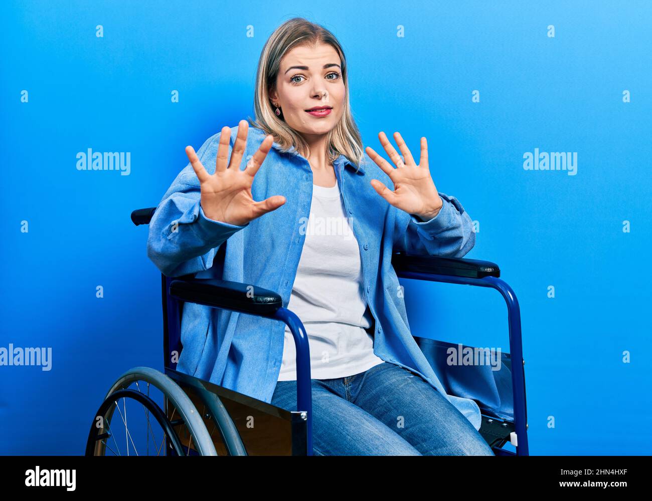 Beautiful caucasian woman sitting on wheelchair afraid and terrified ...