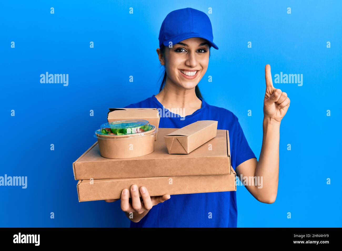 Young hispanic woman holding take away food smiling with an idea or ...