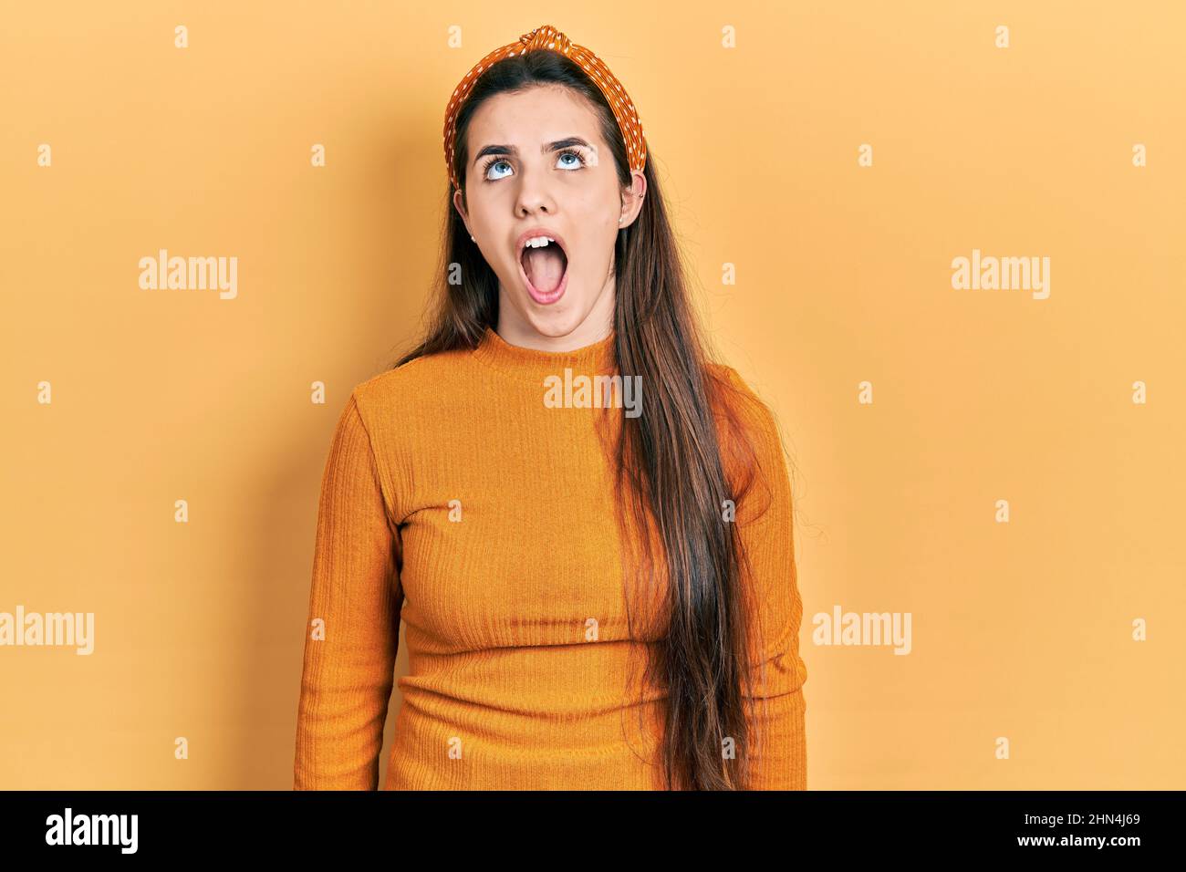 Young brunette teenager wearing casual yellow sweater angry and mad ...