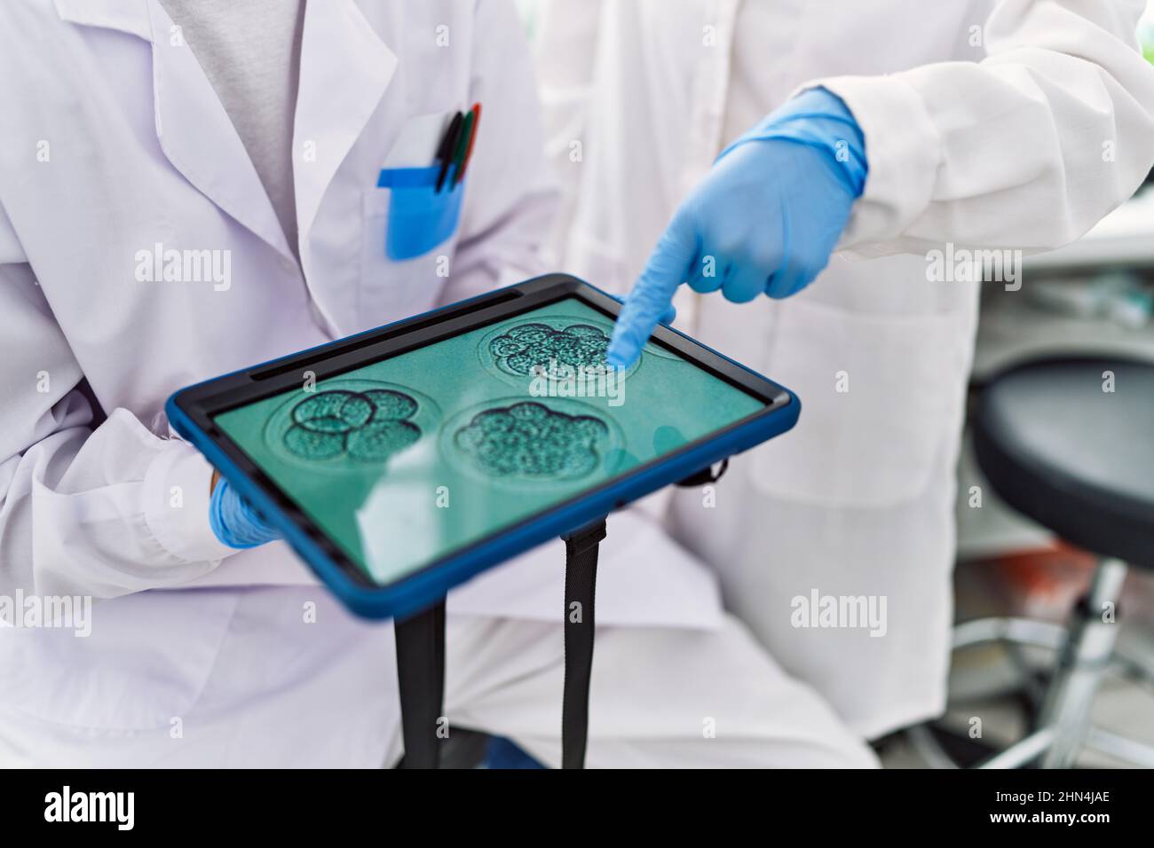 Man and woman partners wearing scientist uniform pointing with finger ...