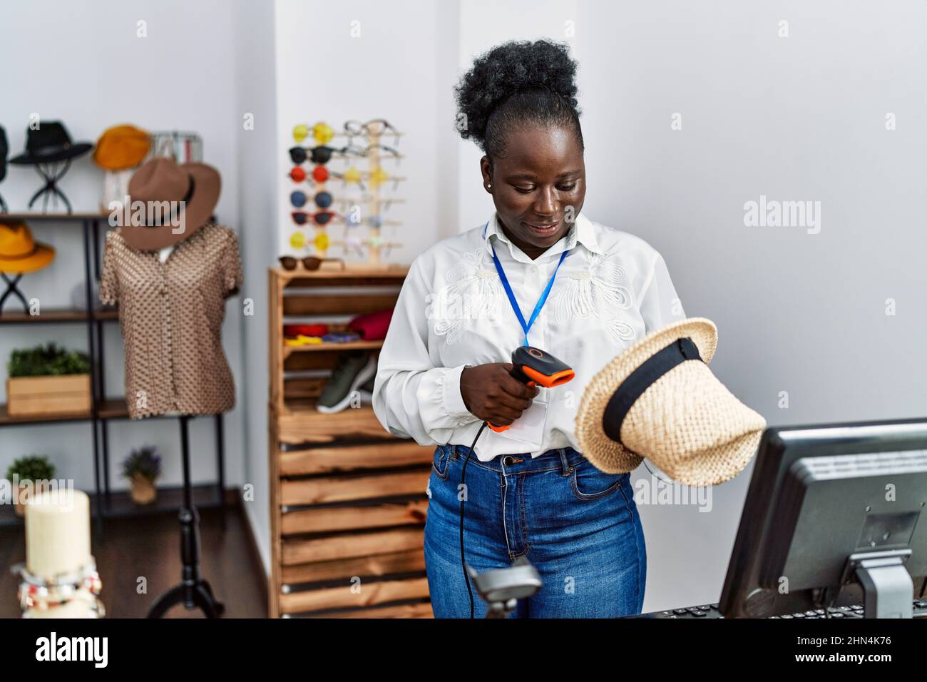 Young african american woman shopkeeper scanning hat using barcode ...