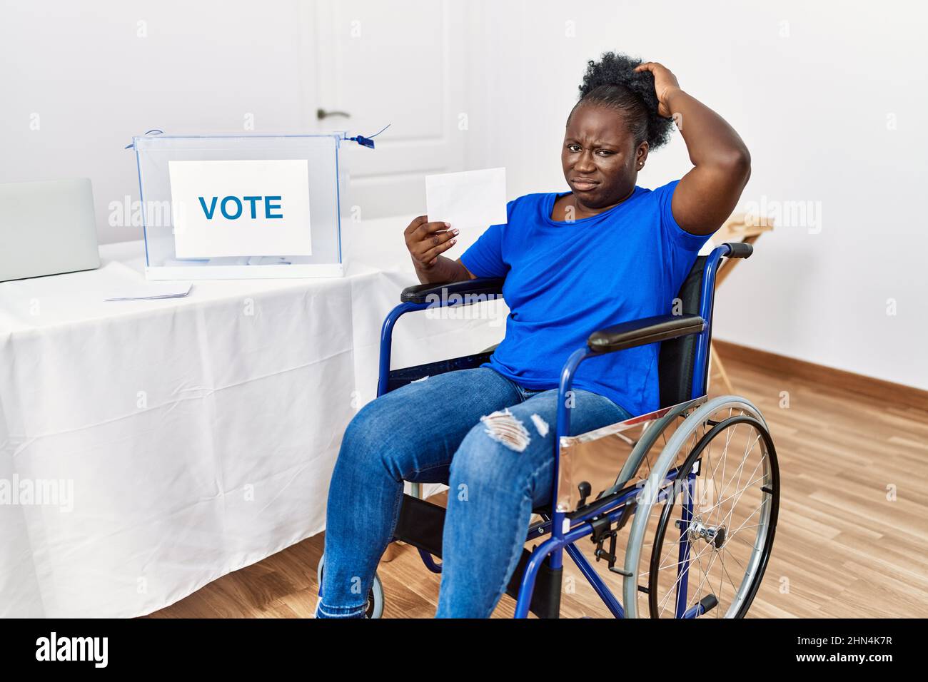 Young african woman sitting on wheelchair voting putting envelop in ...