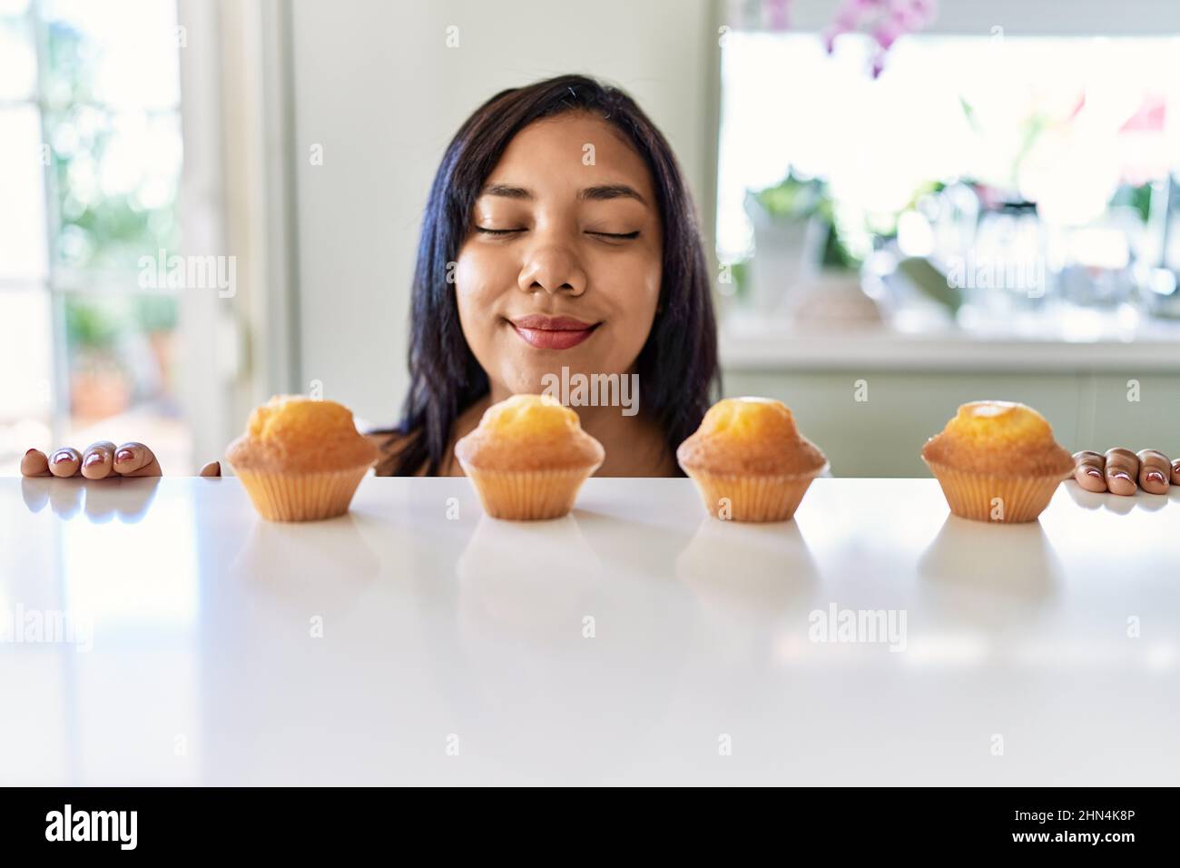 Hispanic brunette woman smelling muffins at the kitchen Stock Photo - Alamy
