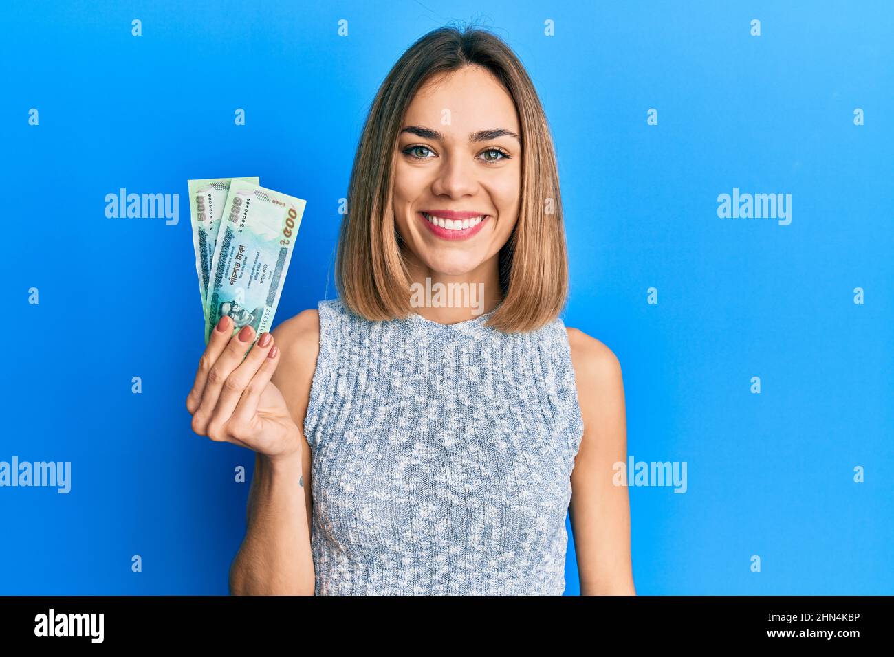 Young caucasian blonde woman holding bangladesh taka banknotes looking ...