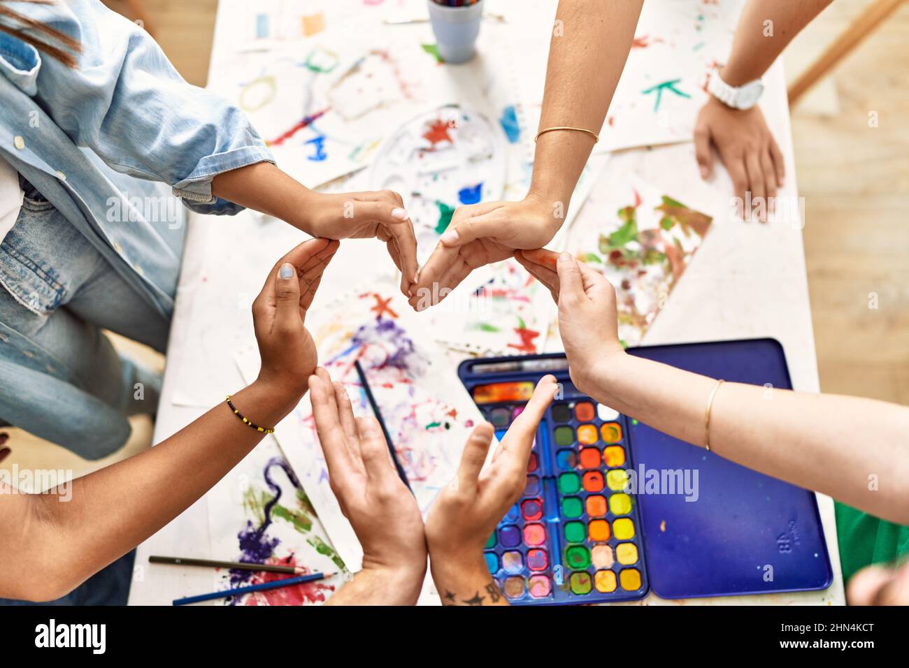 Group of people doing heart sign with hands together at art studio ...