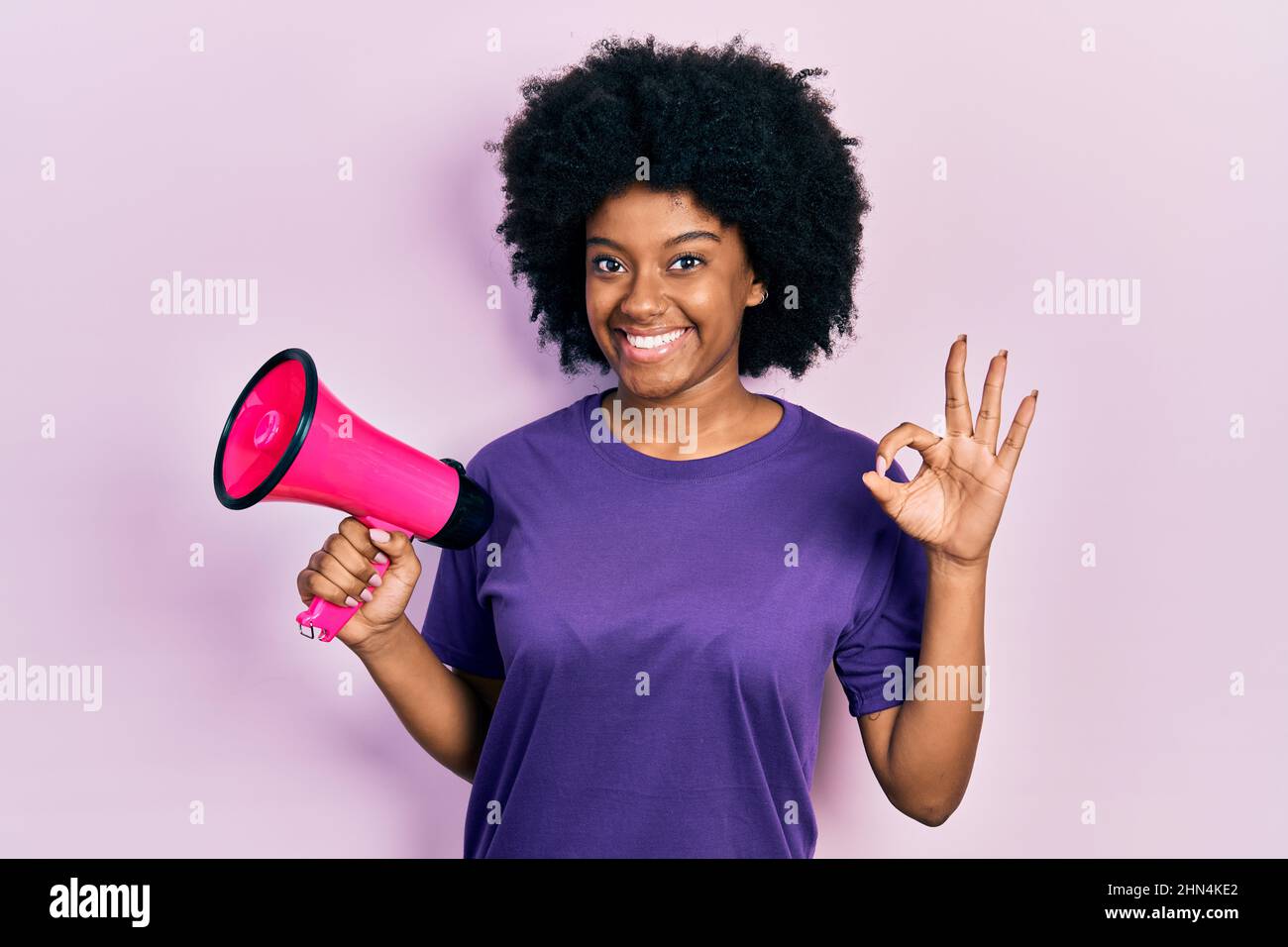 Young african american woman shouting through megaphone doing ok sign ...