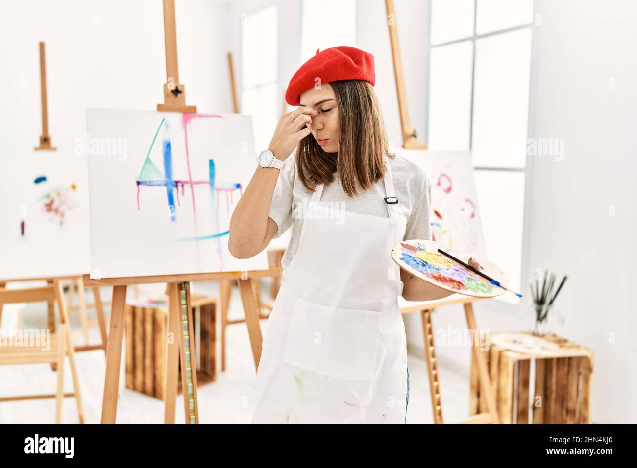 Young artist woman painting on a canvas at art studio tired rubbing ...