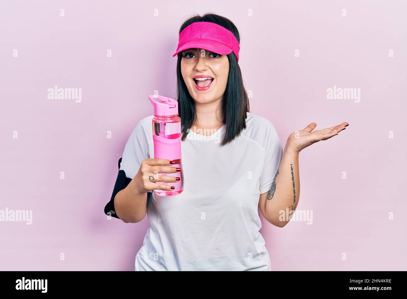 Young hispanic woman wearing sportswear drinking bottle of water ...