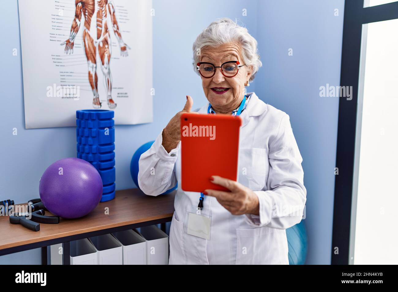 Senior woman with grey hair working physiotherapy clinic doing video ...