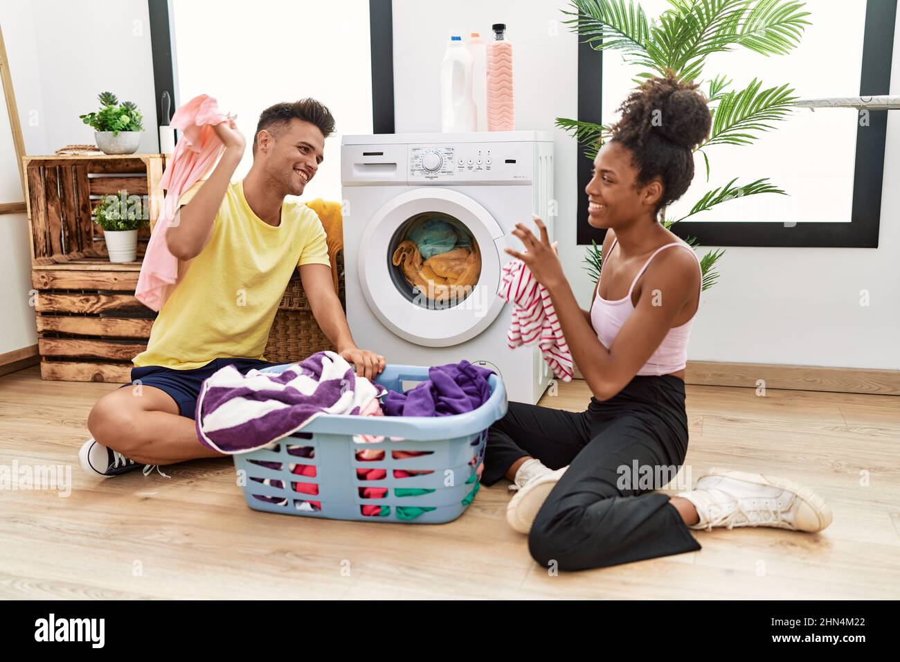 Man and woman couple playing throwing clothes at laundry room Stock ...