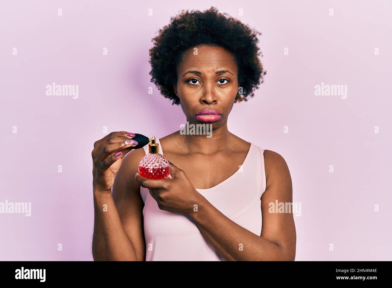 Young african american woman holding perfume depressed and worry for ...