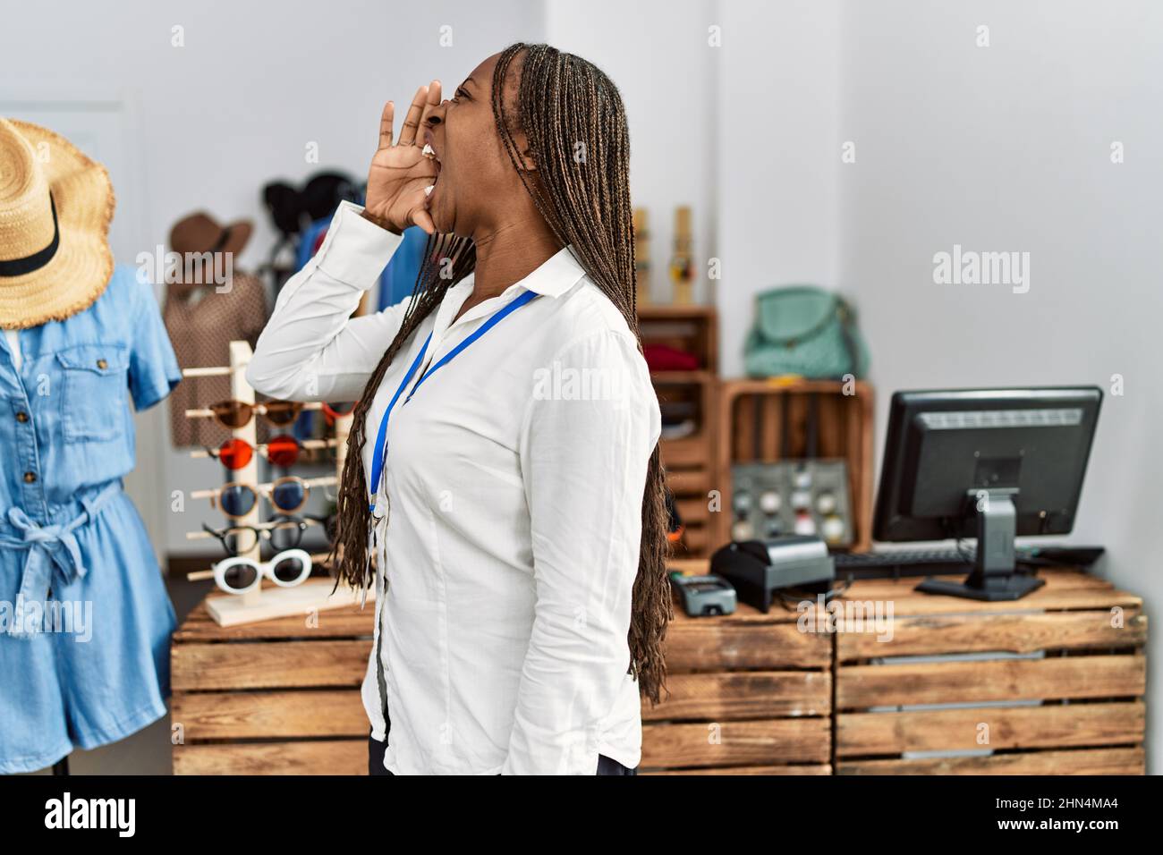 Black woman with braids working as manager at retail boutique shouting ...