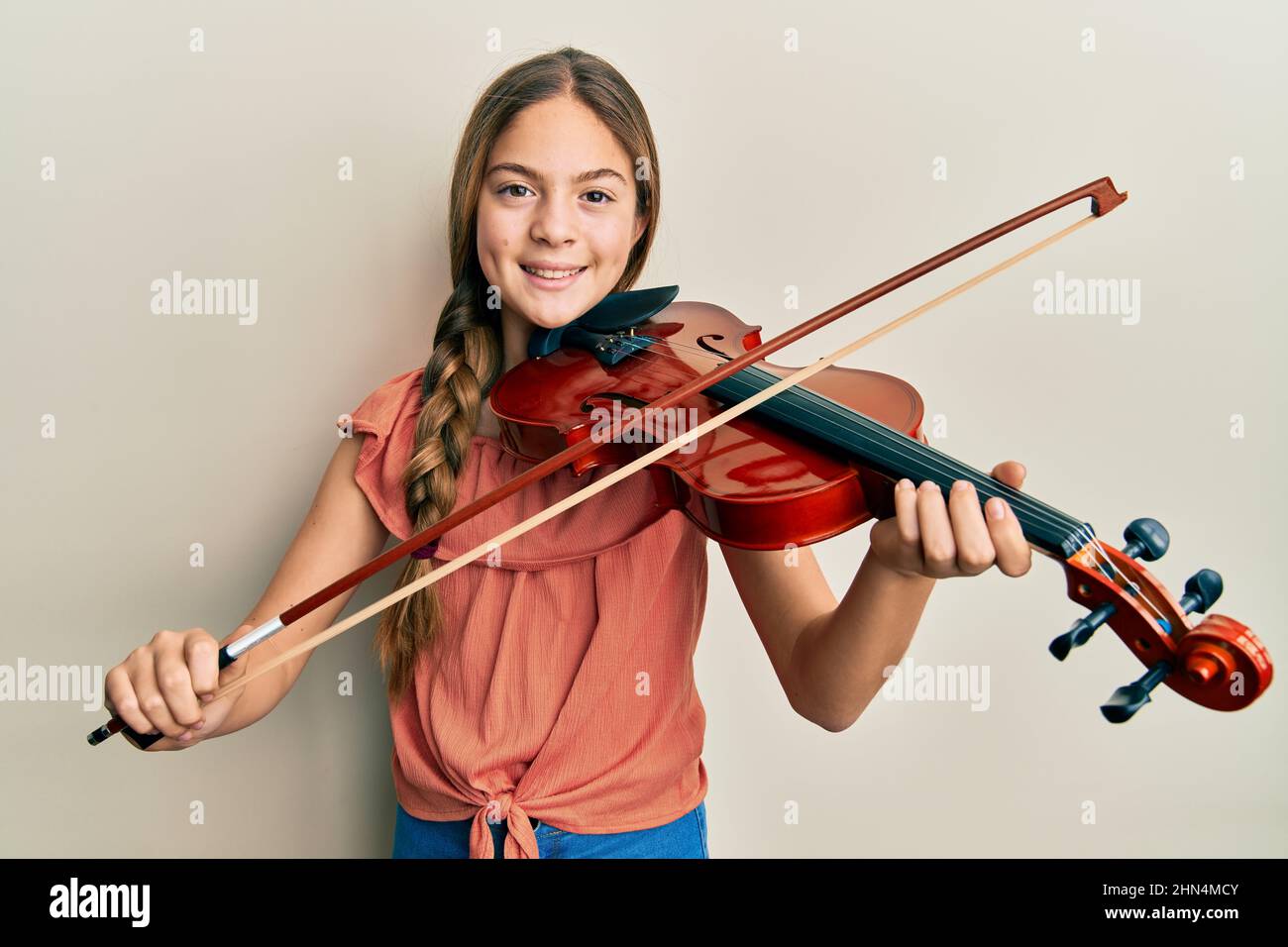 Beautiful brunette little girl playing violin smiling with a happy and ...