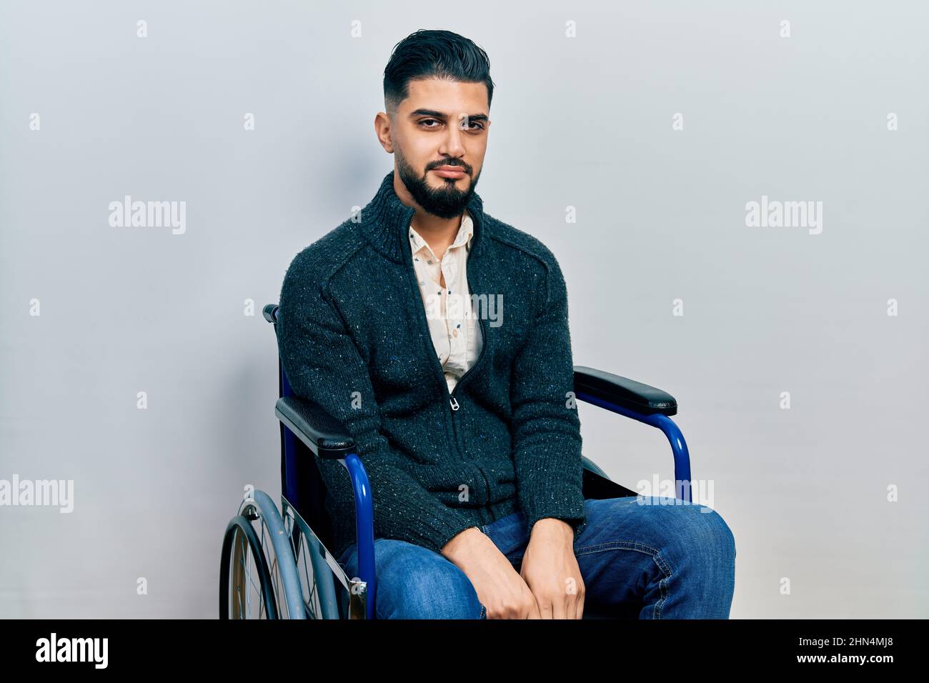 Handsome man with beard sitting on wheelchair depressed and worry for ...