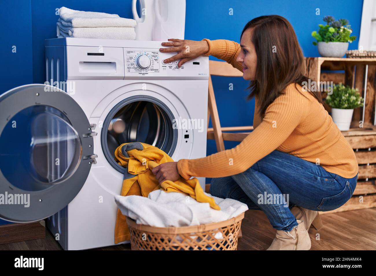 Middle age woman smiling confident washing clothes at laundry room ...