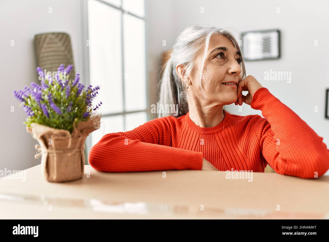 Middle age grey-haired woman smiling confident leaning on package at ...