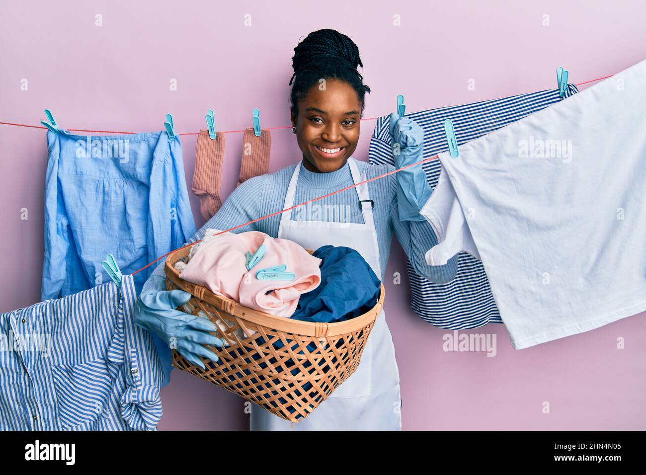 African american woman with braided hair doing laundry holding wicker ...