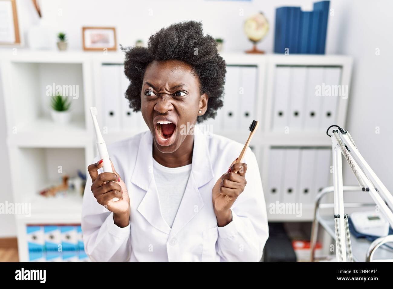 African dentist woman holding electric toothbrush and normal toothbrush ...