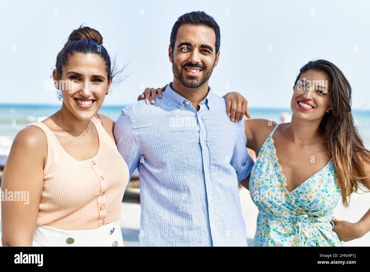 Three young hispanic friends smiling happy and hugging at the beach ...