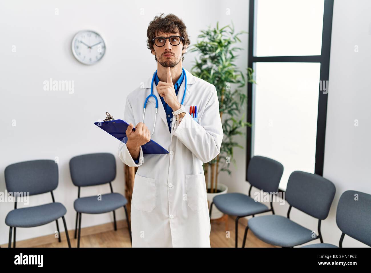Young hispanic doctor man at waiting room thinking concentrated about ...